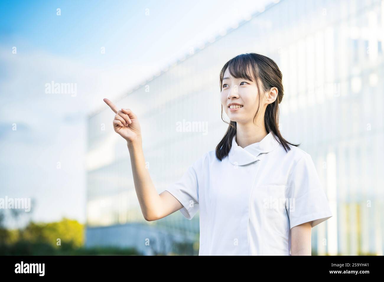 Woman in white coat striking a pointing pose Stock Photo - Alamy