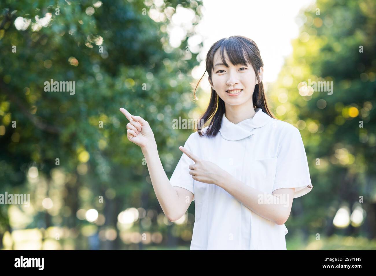 Woman in white coat striking a pointing pose Stock Photo - Alamy