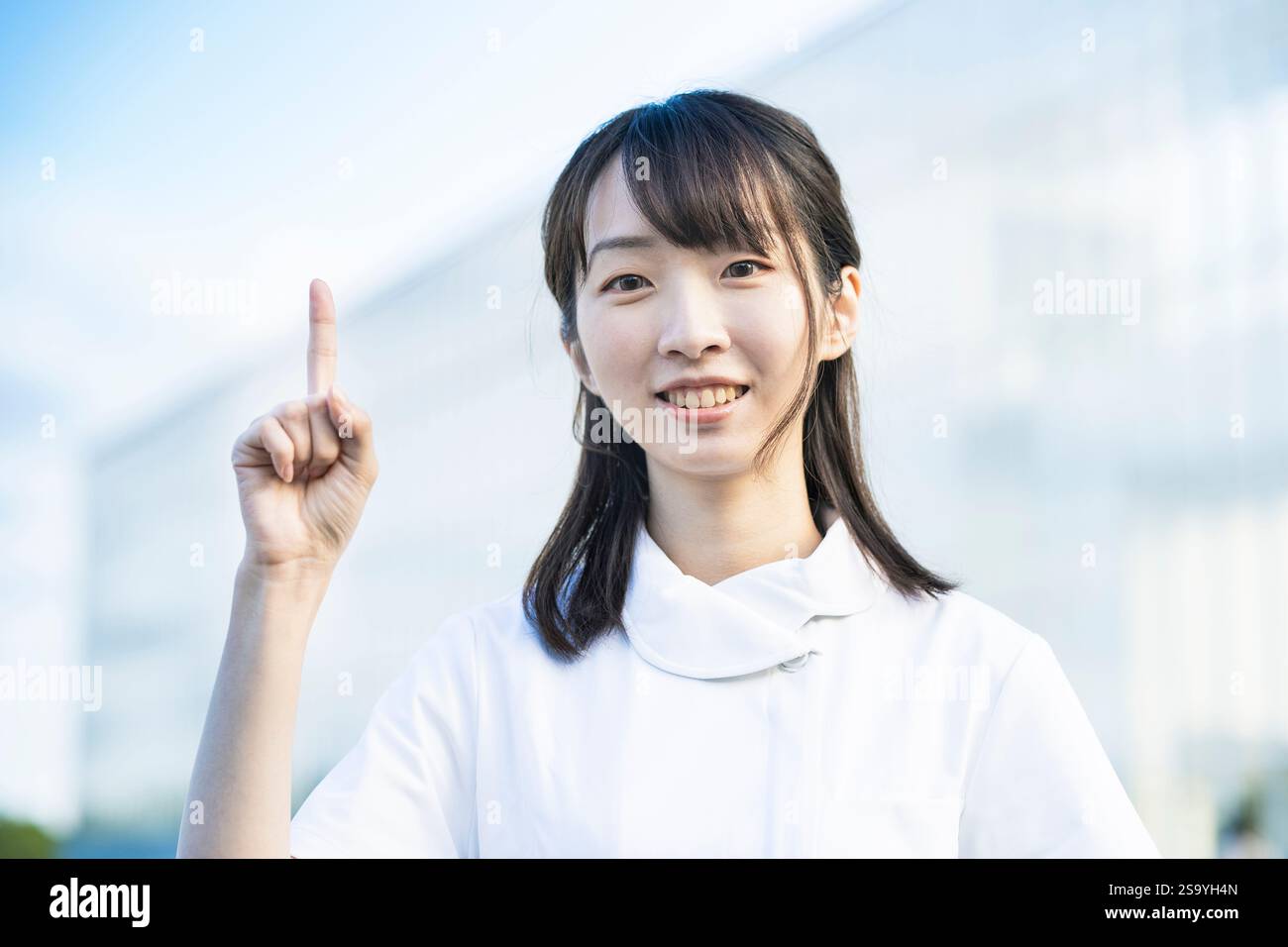 Woman in white coat striking a pointing pose Stock Photo - Alamy