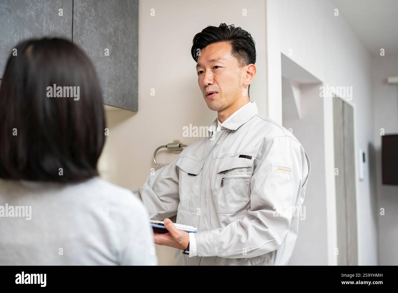 Man in work clothes explaining to woman (plumber Stock Photo - Alamy
