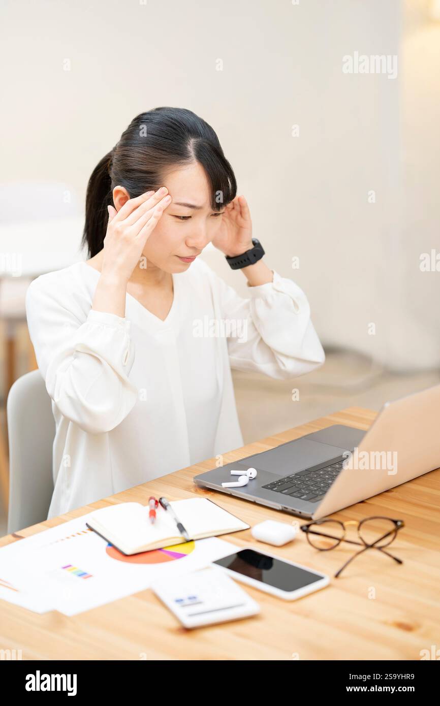 Woman suffering from headache at work Stock Photo - Alamy
