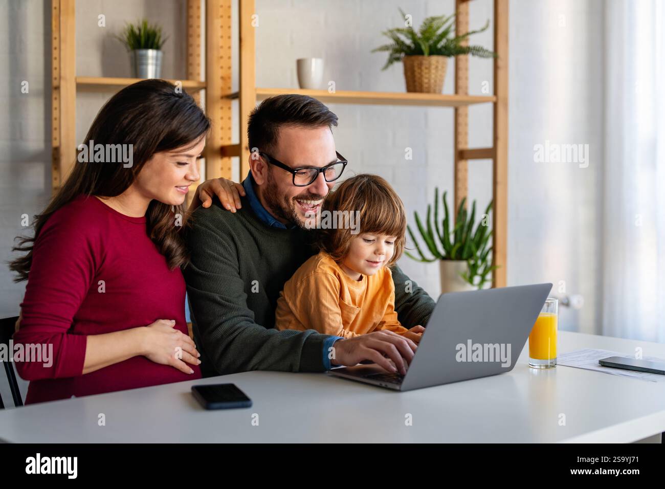 Happy family with kid having fun using laptop together, parents and ...