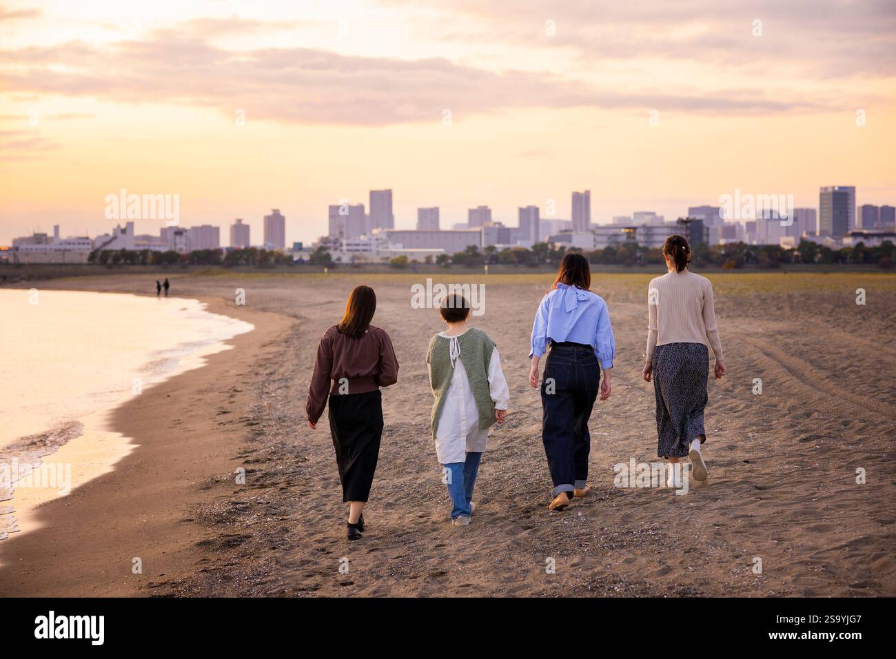 Four women walking along the seafront, cuddling up to each other in the ...