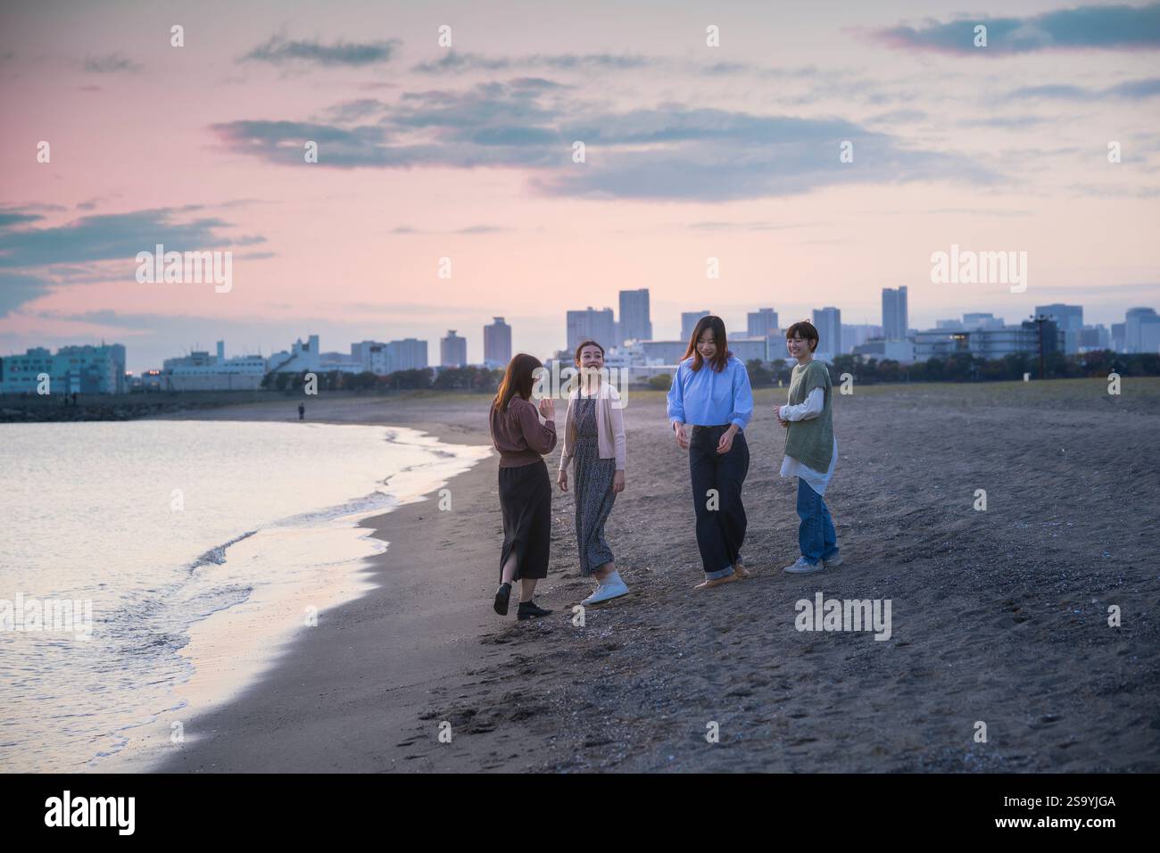 Four women walking along the seafront, cuddling up to each other in the ...