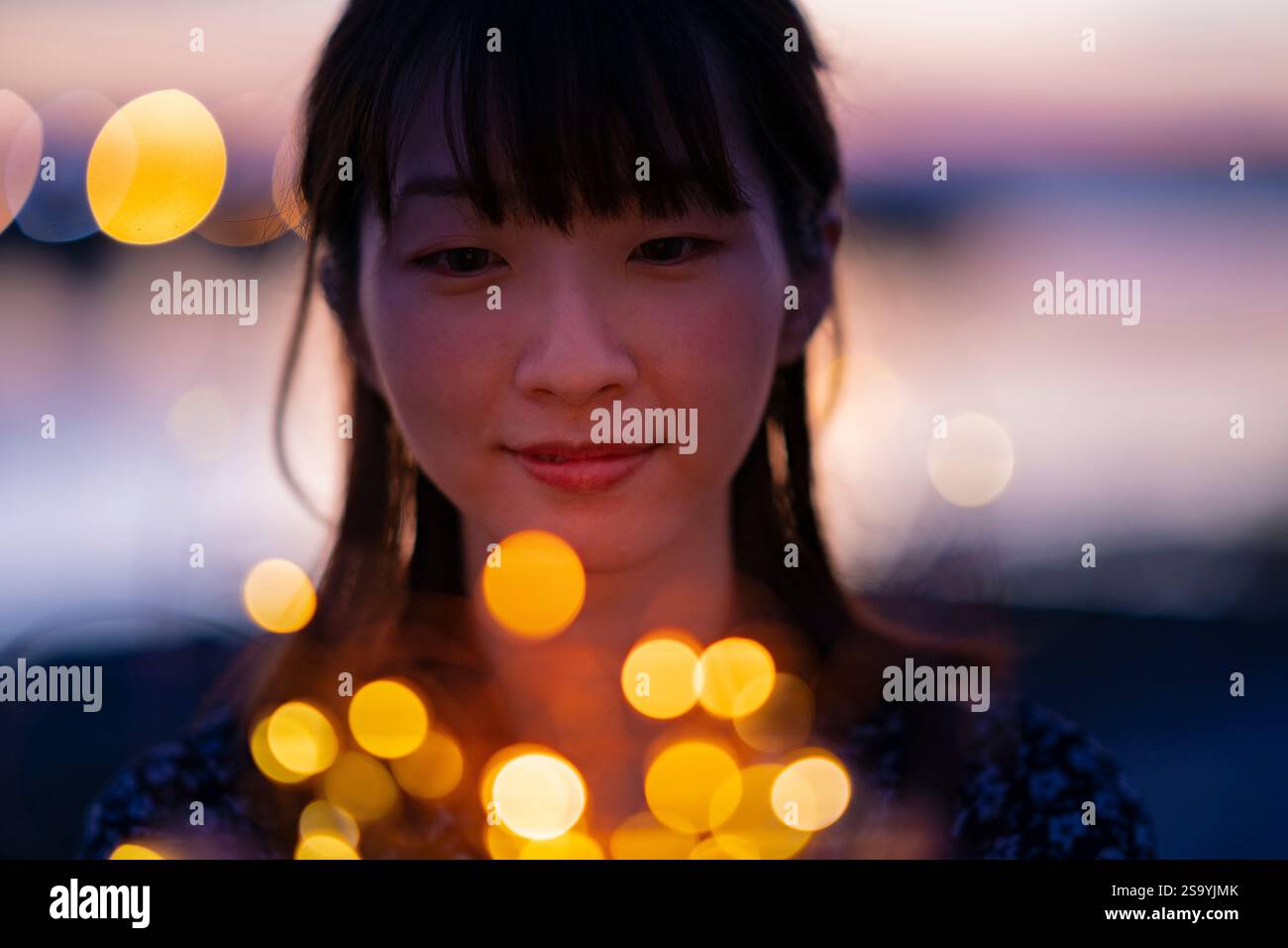 Young woman wrapping her hands around an illuminated light Stock Photo ...