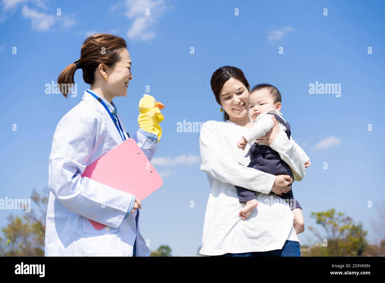 Parent and child talking to woman in white coat holding puppet doll ...