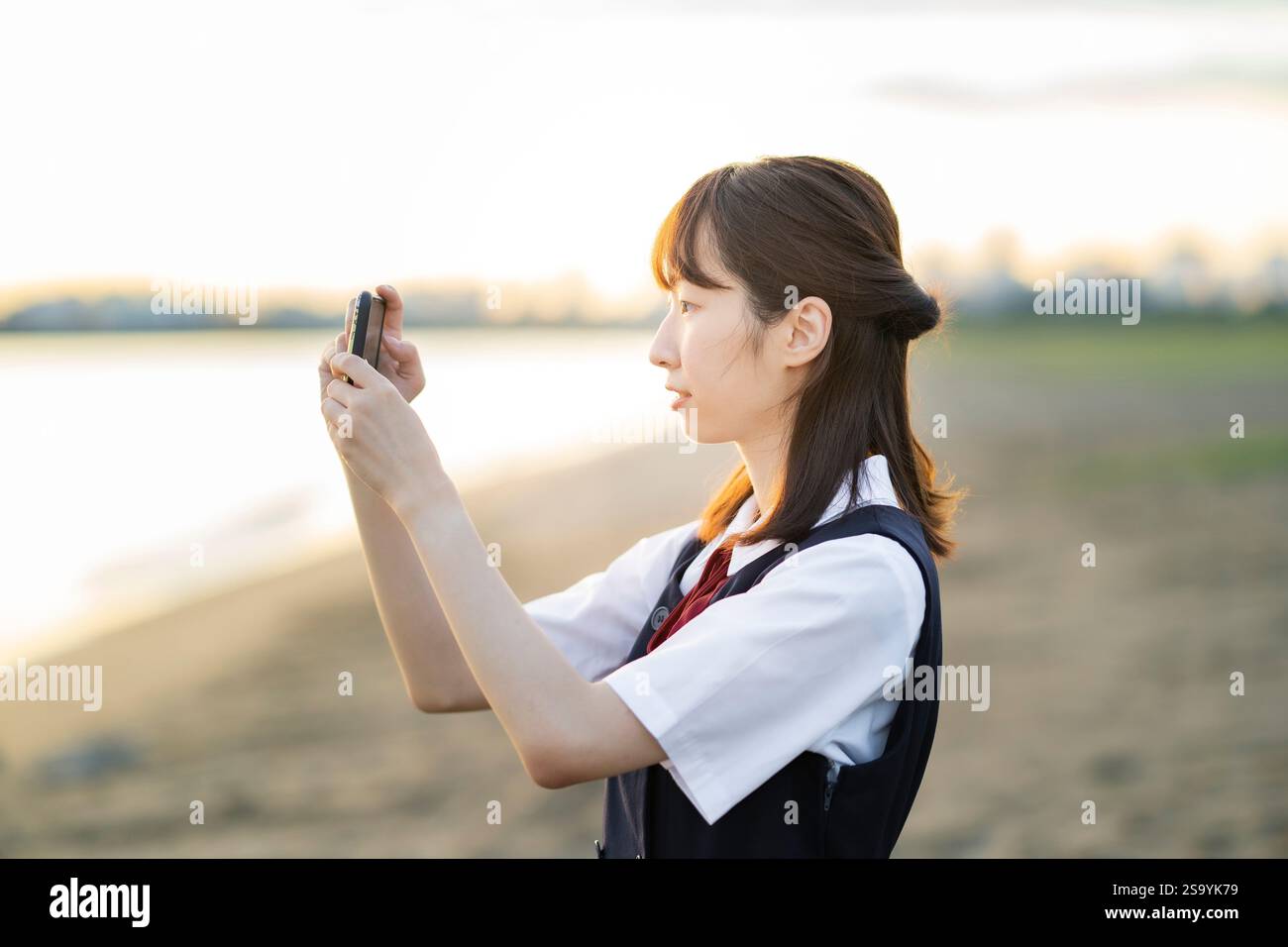 Asian female high school student taking photos of the scenery with her ...