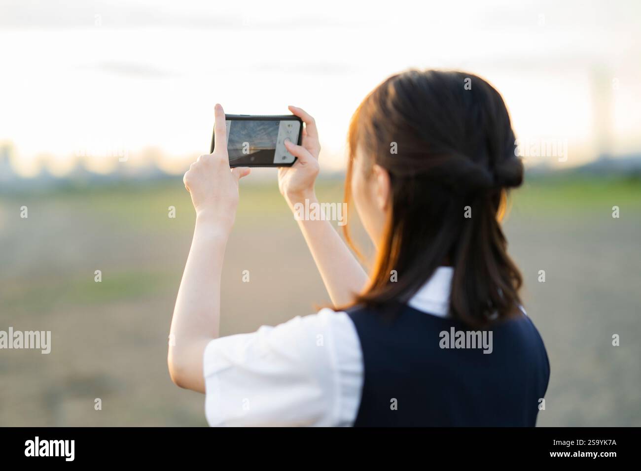 Asian female high school student taking photos of the scenery with her ...