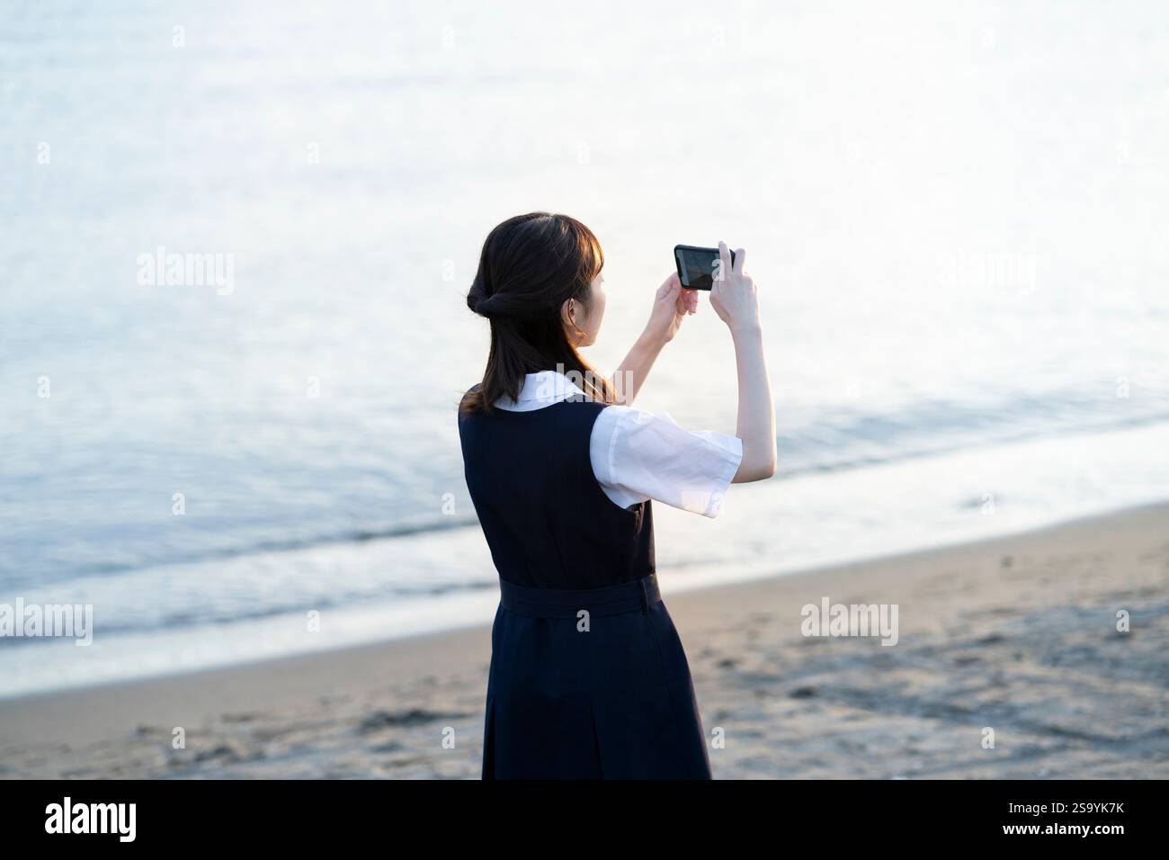 Asian female high school student taking photos of the scenery with her ...