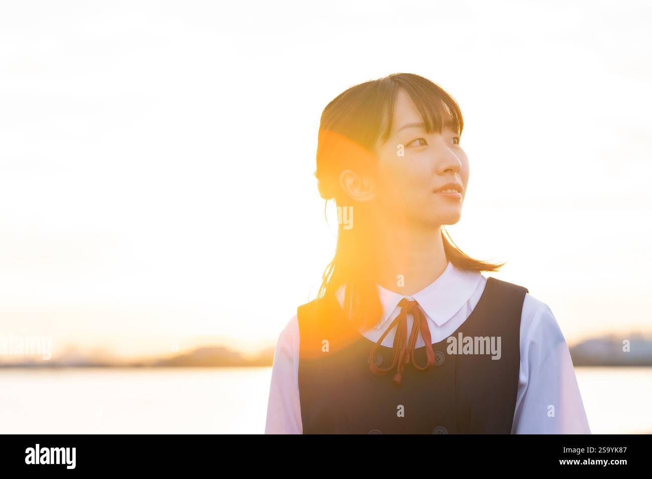 Asian female high school student surrounded by the setting sun Stock ...