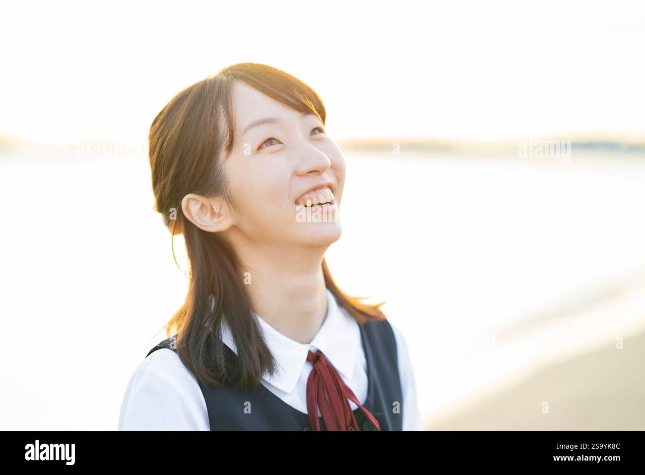 Asian female high school student surrounded by the setting sun Stock ...
