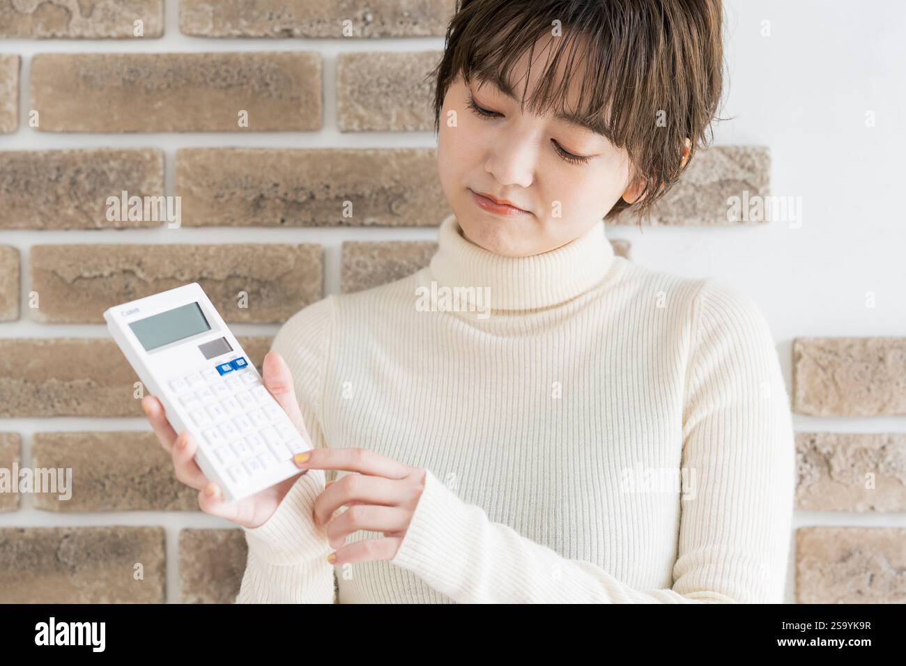 Young woman with a calculator and a stern expression on her face Stock ...