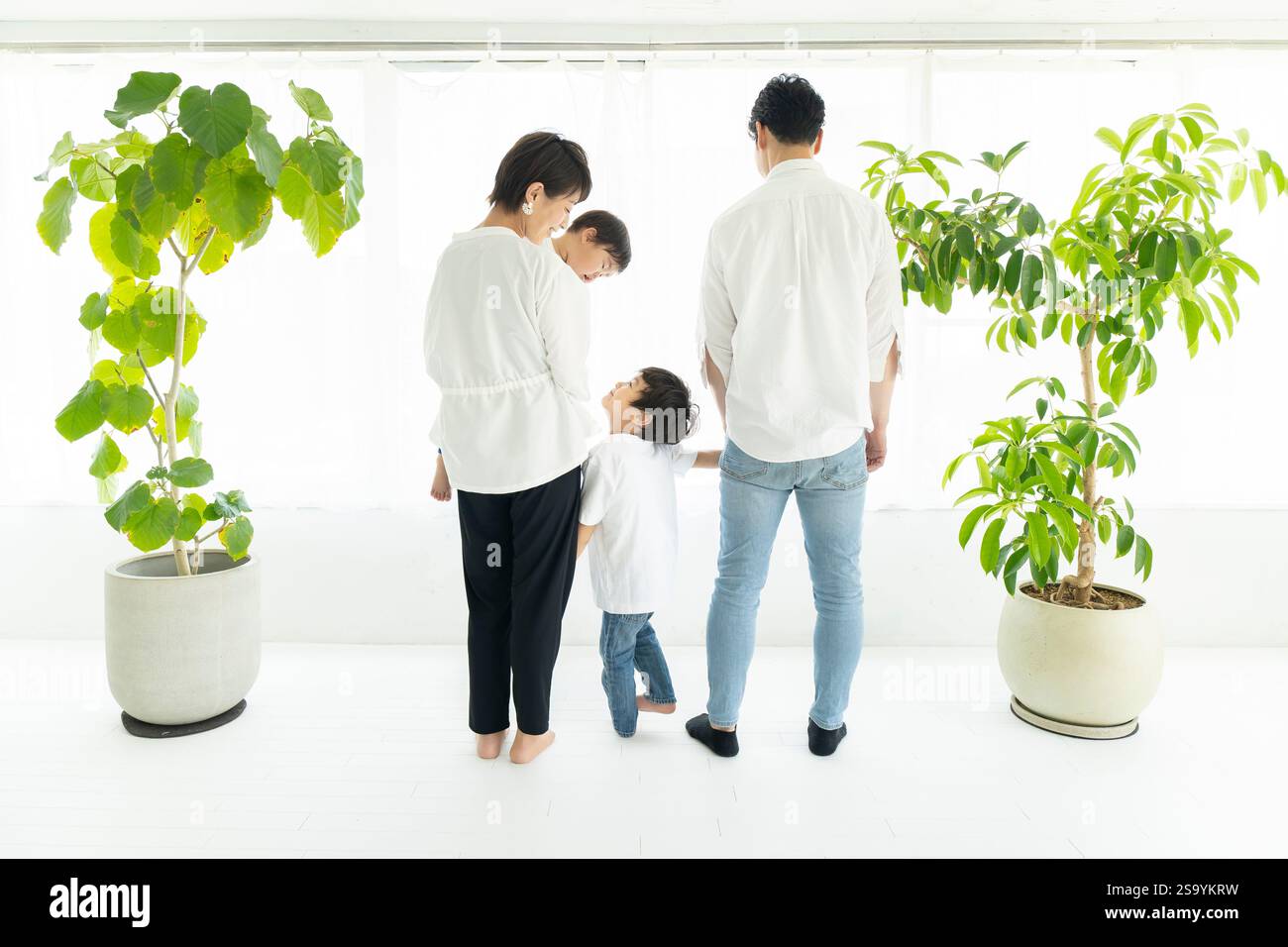 Backs of family members standing side by side by the window Stock Photo ...