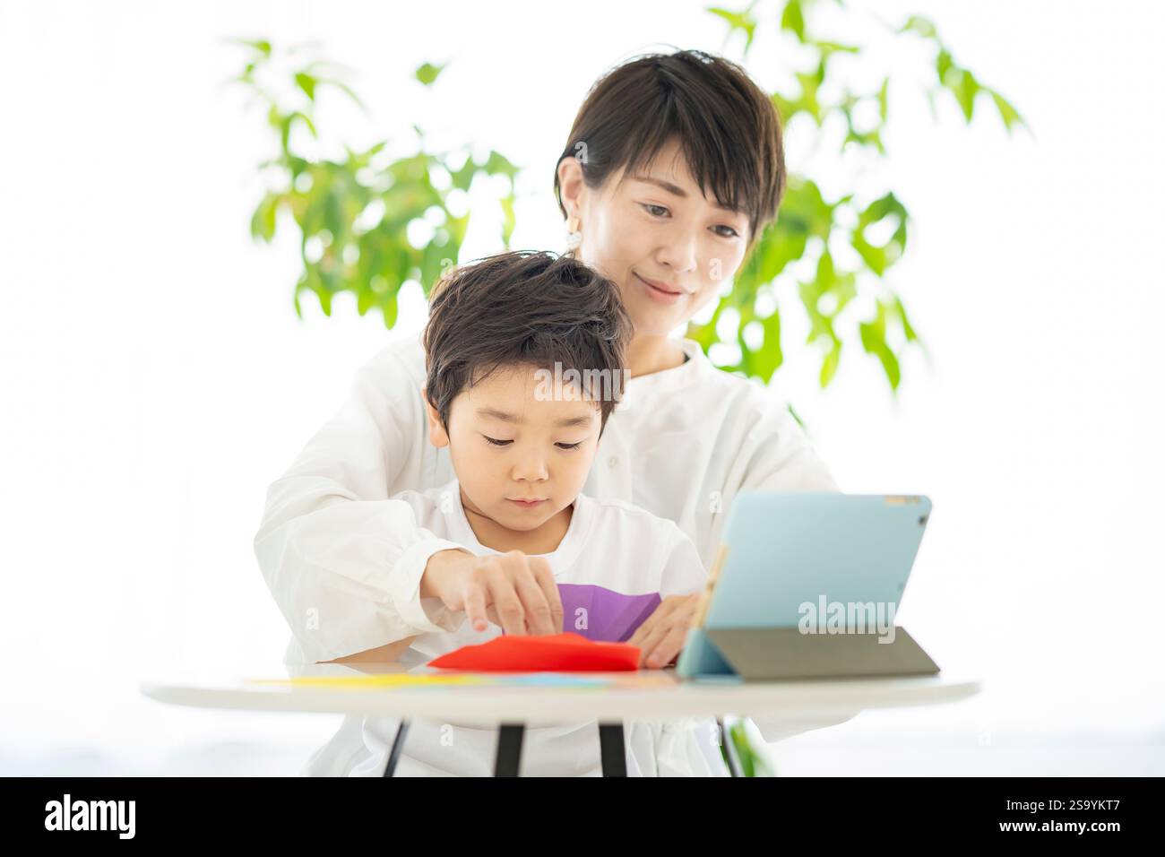 Parents and children doing origami while looking at a tablet PC Stock ...