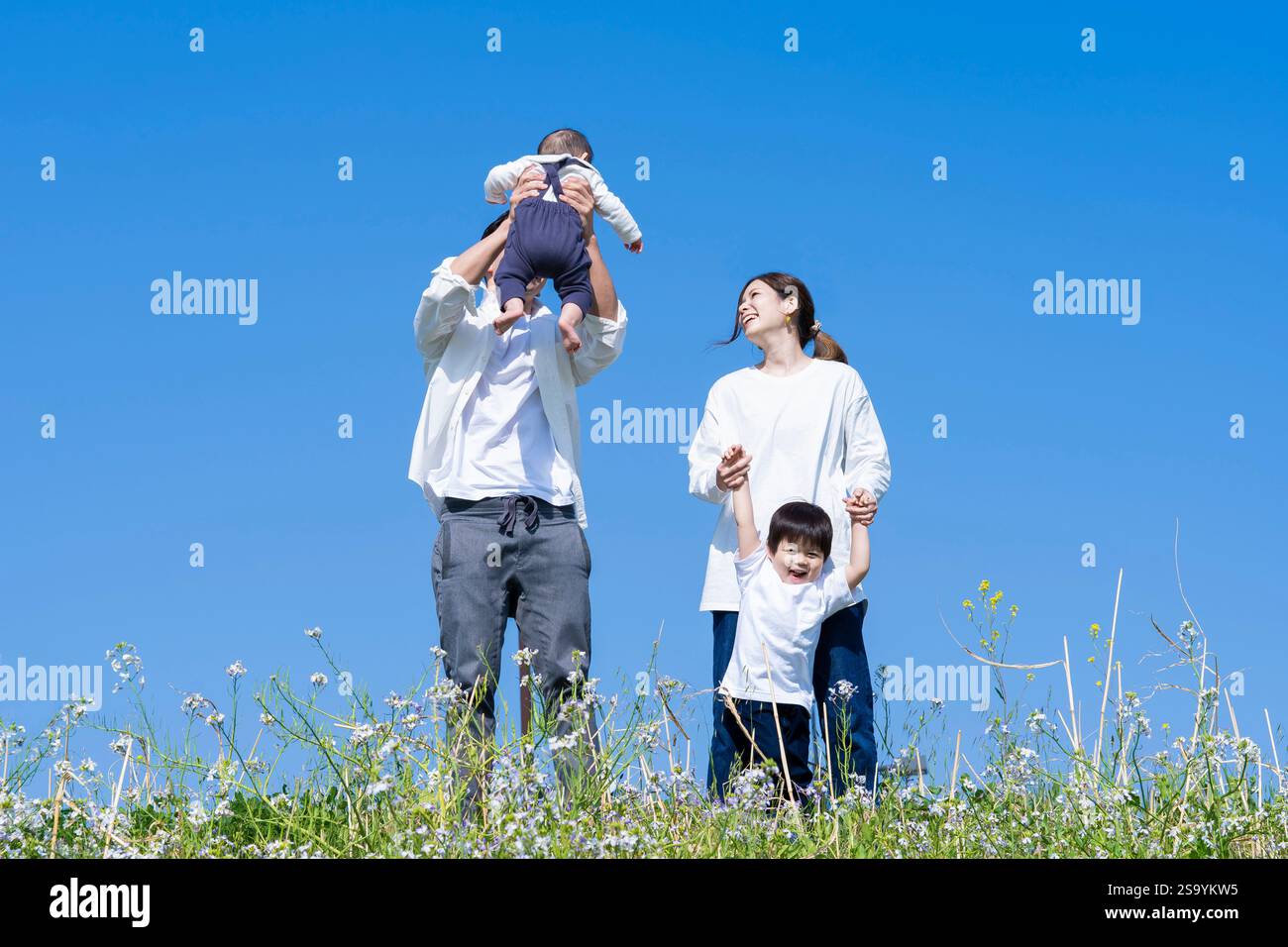 Family strolling happily and excitedly under a blue sky Stock Photo - Alamy