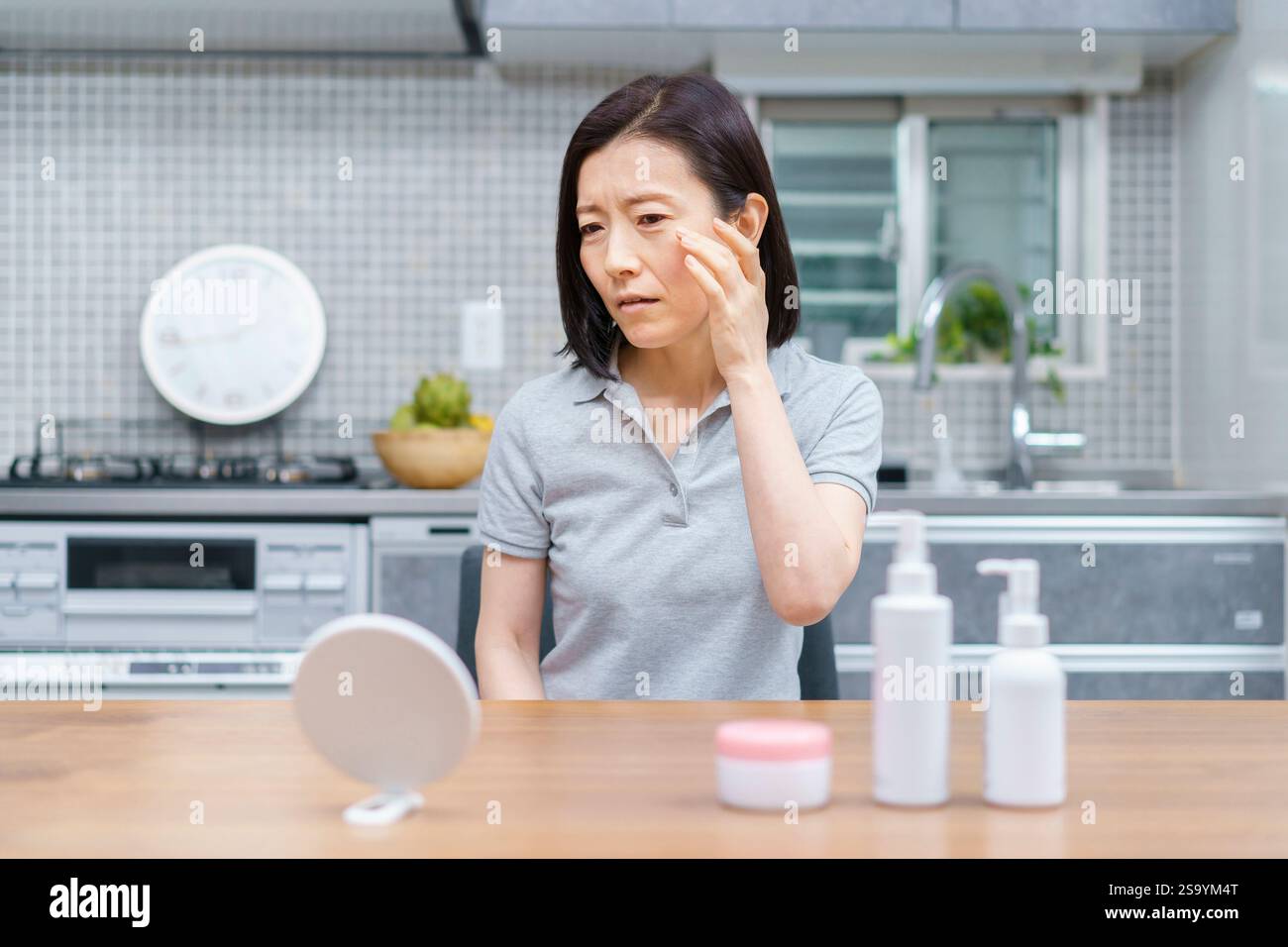 Middle-aged woman checking her skin with anxious expression Stock Photo ...