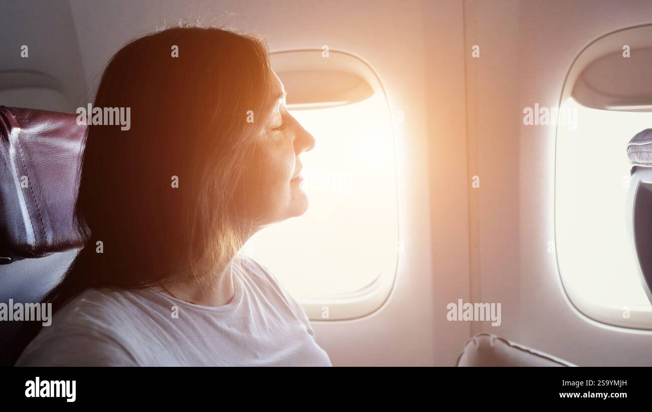 Woman relaxing looking out airplane window Stock Photo - Alamy