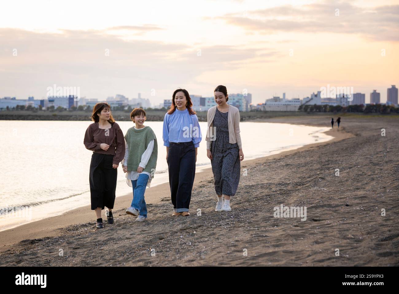 Four women walking along the seafront, cuddling up to each other in the ...