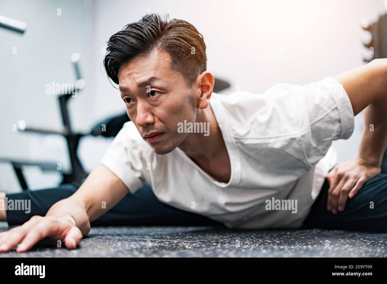 Man doing stretching exercises at the gym Stock Photo - Alamy