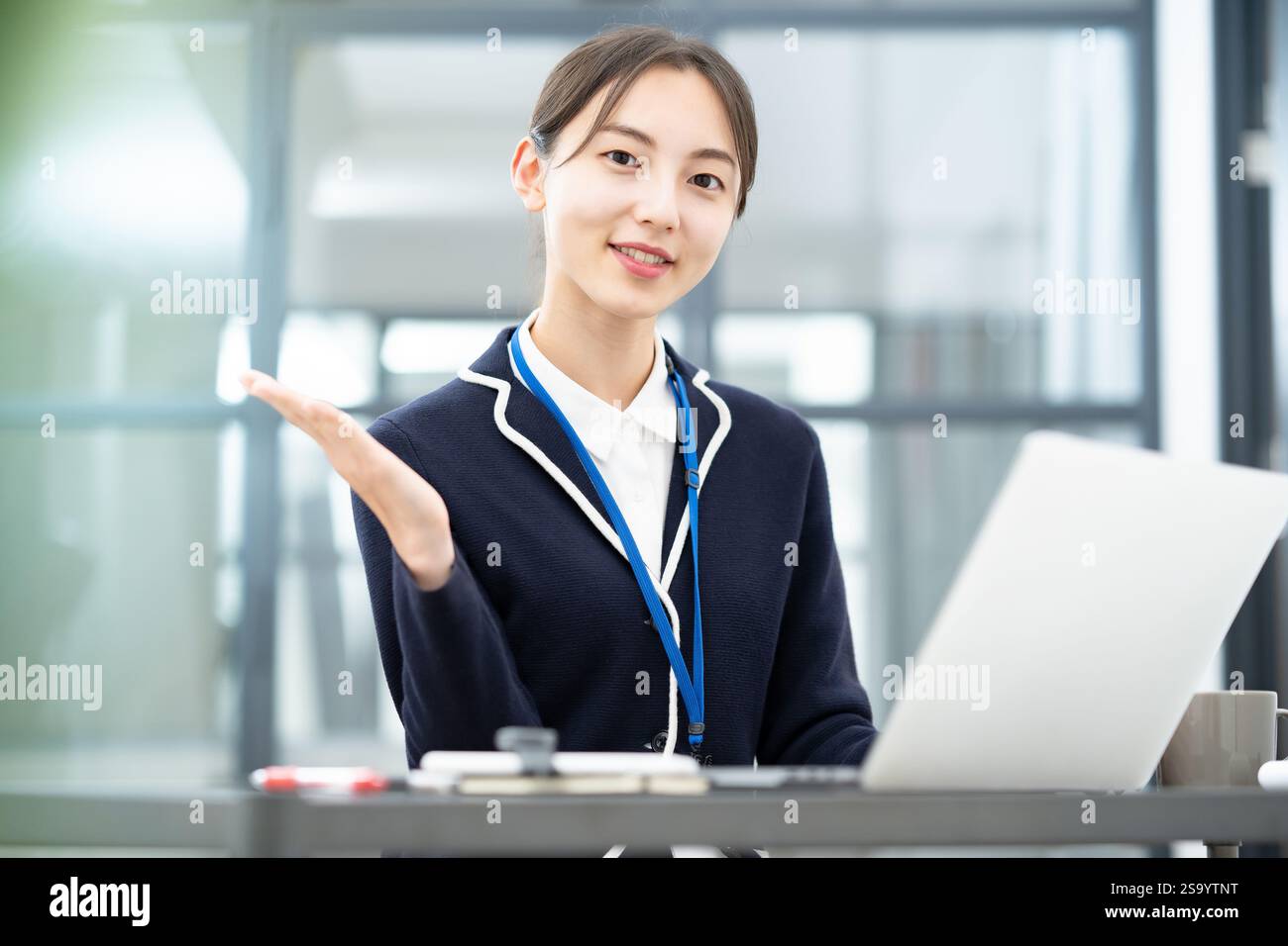Woman posing as a receptionist/guide in an office Stock Photo - Alamy