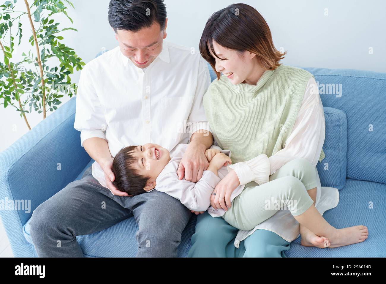 Child being pampered by parents on a sofa Stock Photo - Alamy