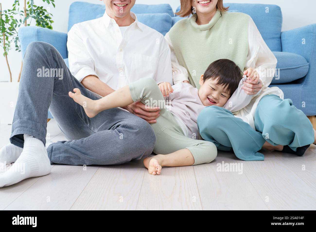 Child being pampered by parents on a sofa Stock Photo - Alamy