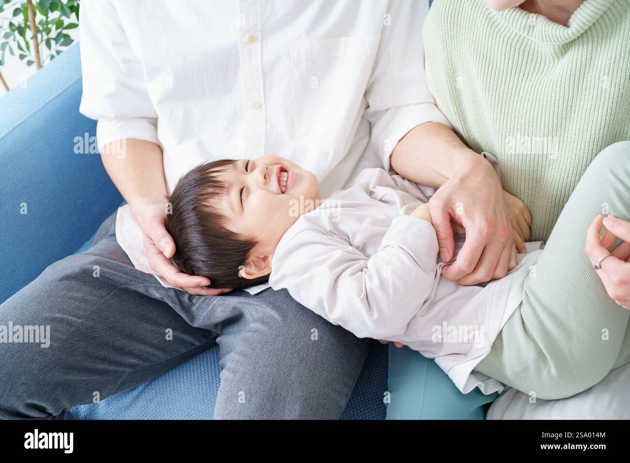 Child being pampered by parents on a sofa Stock Photo - Alamy