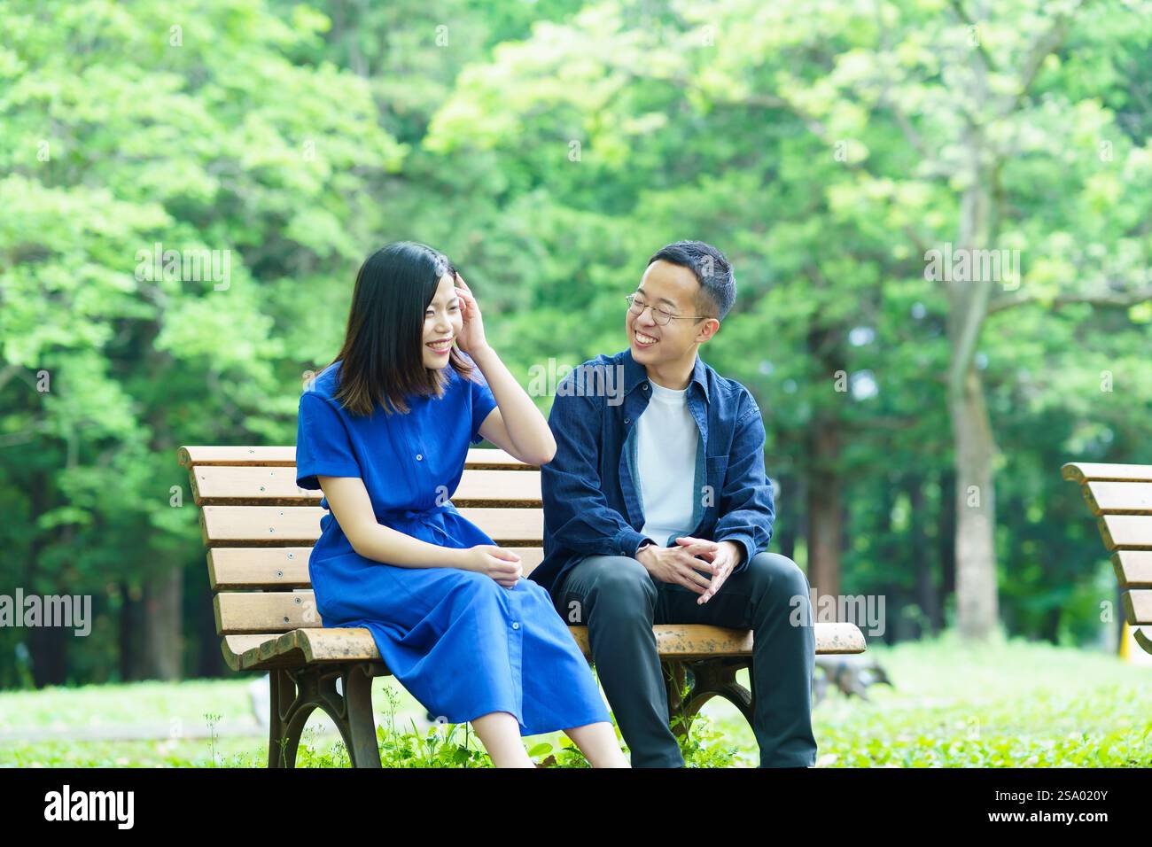 Young couple chatting on park bench Stock Photo - Alamy