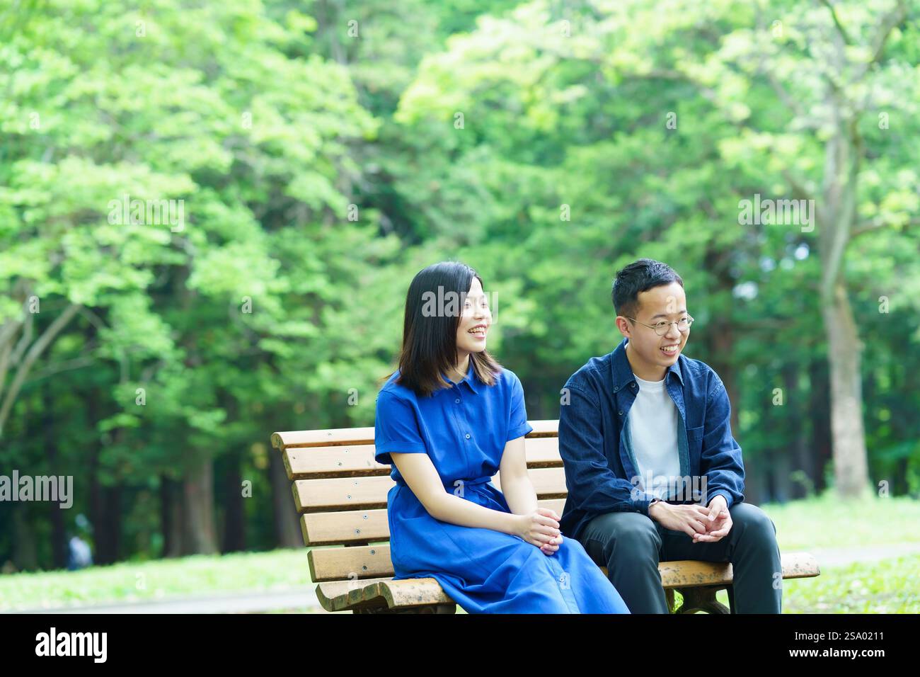 Young couple chatting on park bench Stock Photo - Alamy