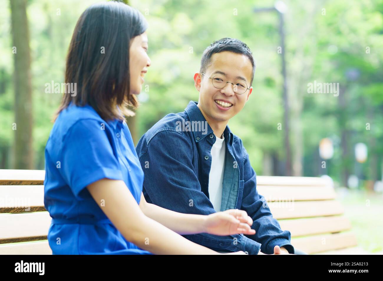 Young couple chatting on park bench Stock Photo - Alamy