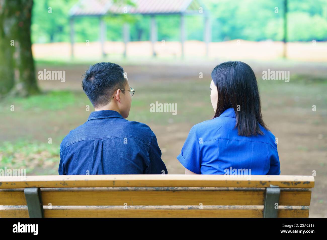 Young couple chatting on park bench, back view Stock Photo - Alamy