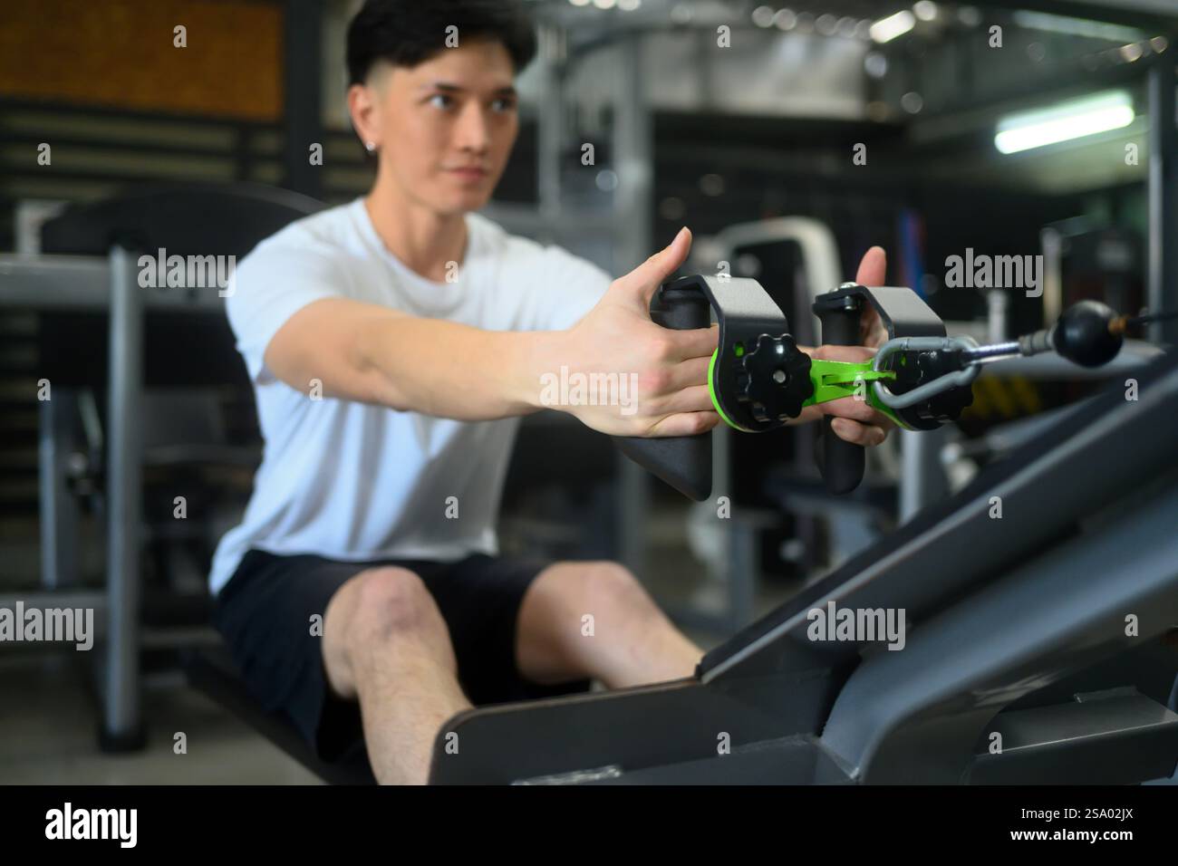 Young athlete doing exercise and pulling weights in seated cable row ...