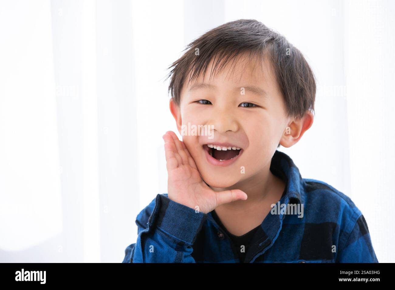 Boy talking loudly with hand over mouth Stock Photo - Alamy