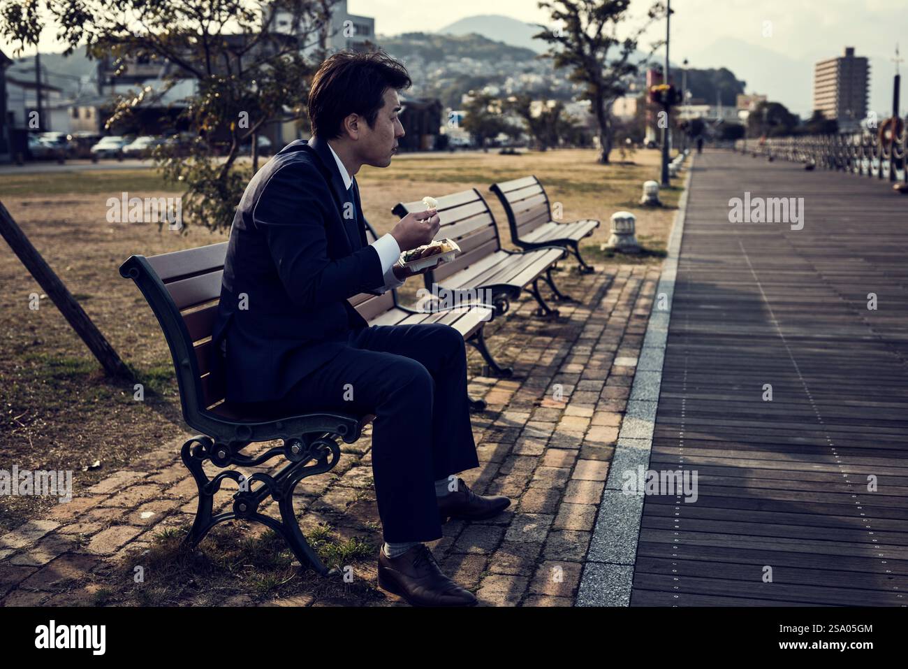Man eating a convenience store lunch on a park bench Stock Photo - Alamy