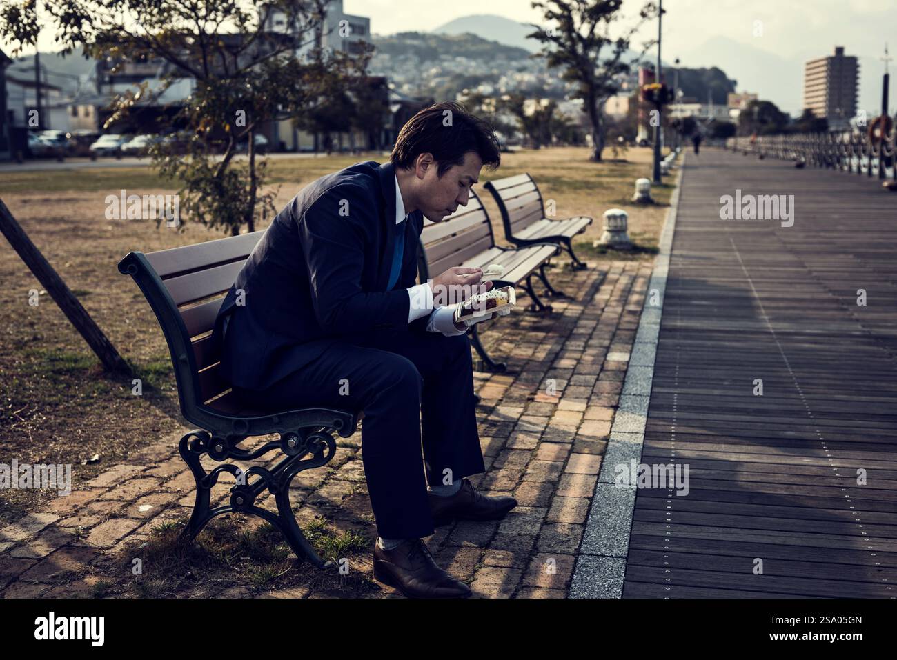 Man eating a convenience store lunch on a park bench Stock Photo - Alamy