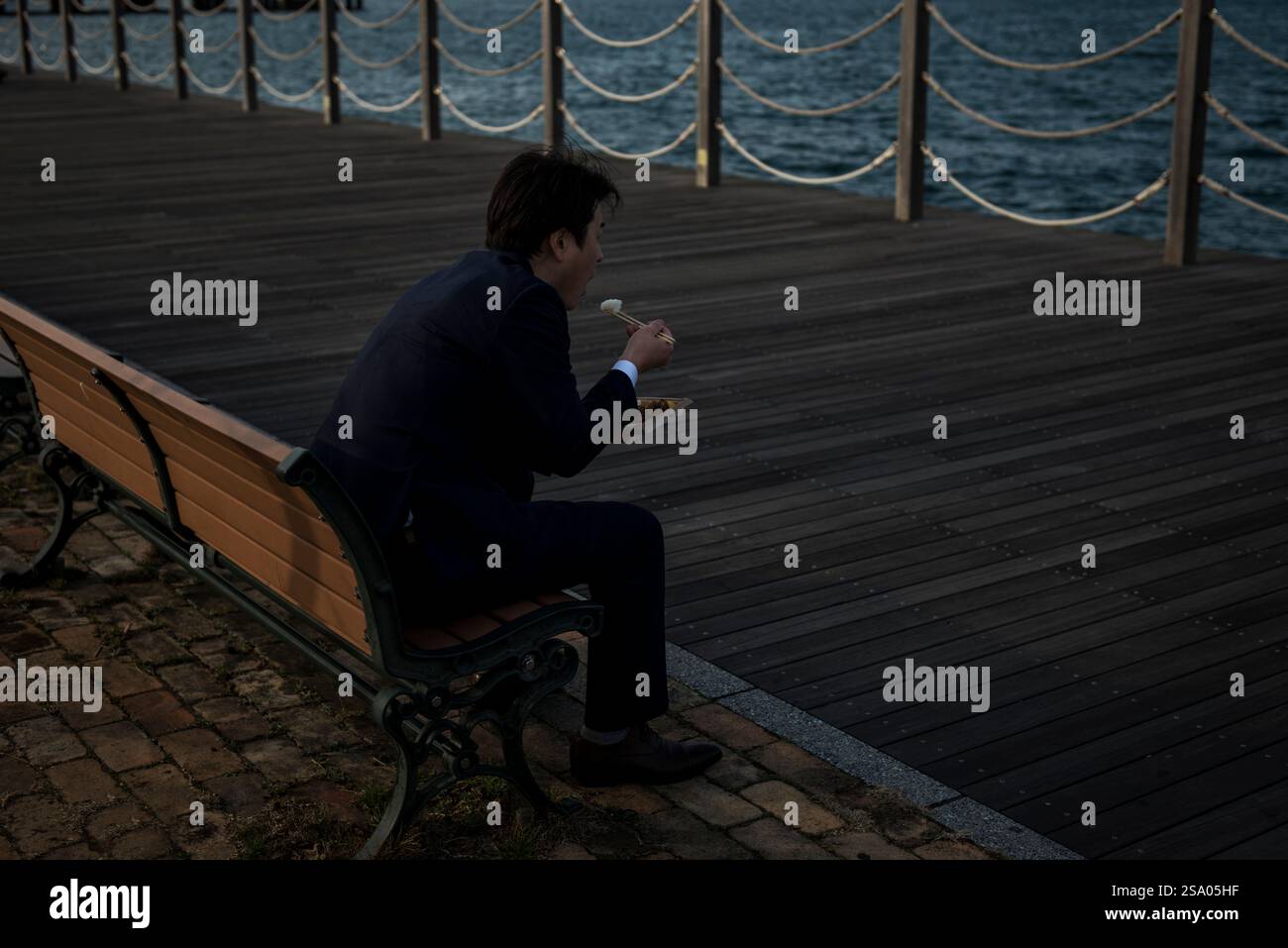 Man eating a convenience store lunch on a park bench Stock Photo - Alamy