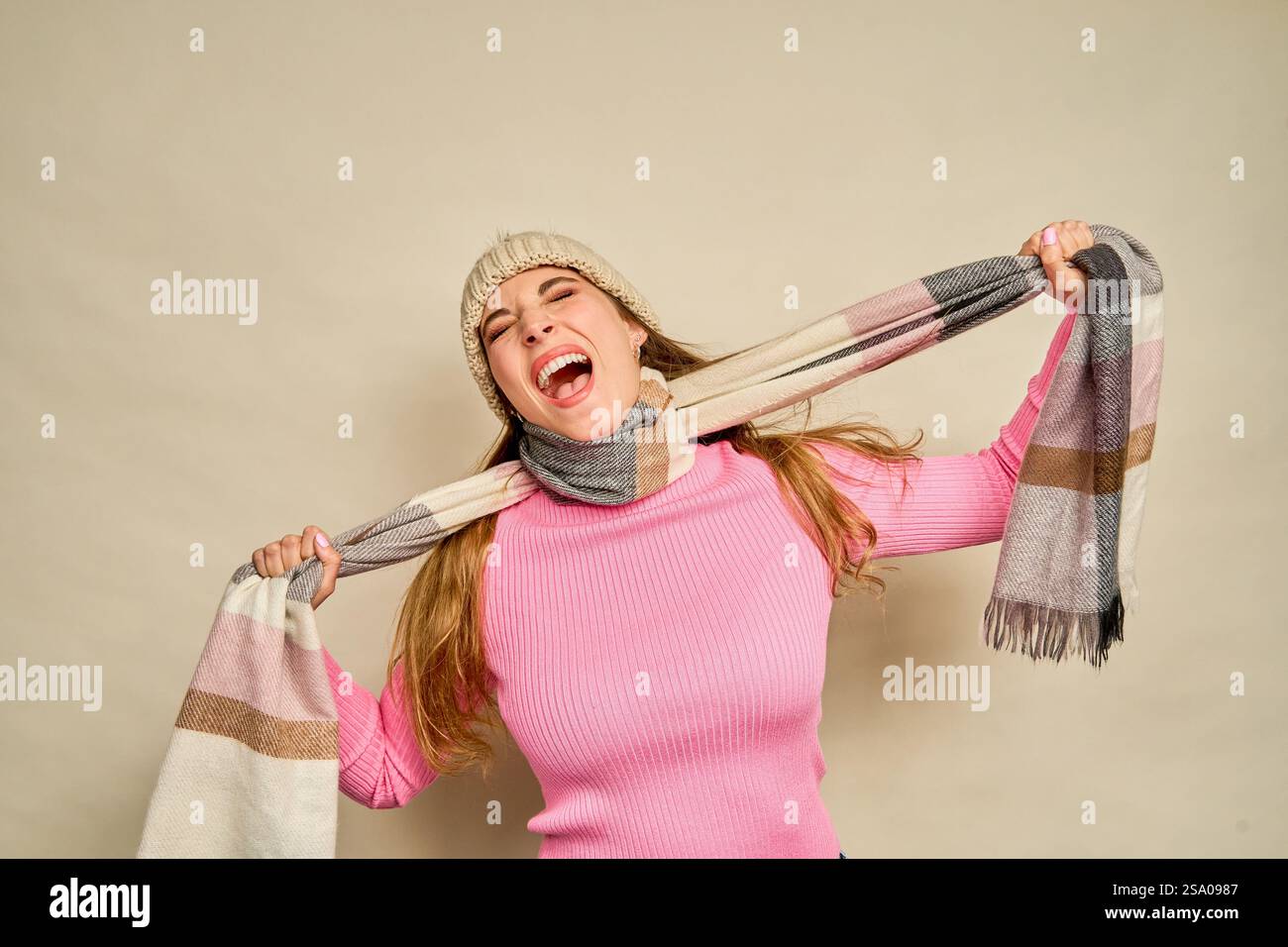 Studio portrait of young woman wearing winter clothes screaming and ...