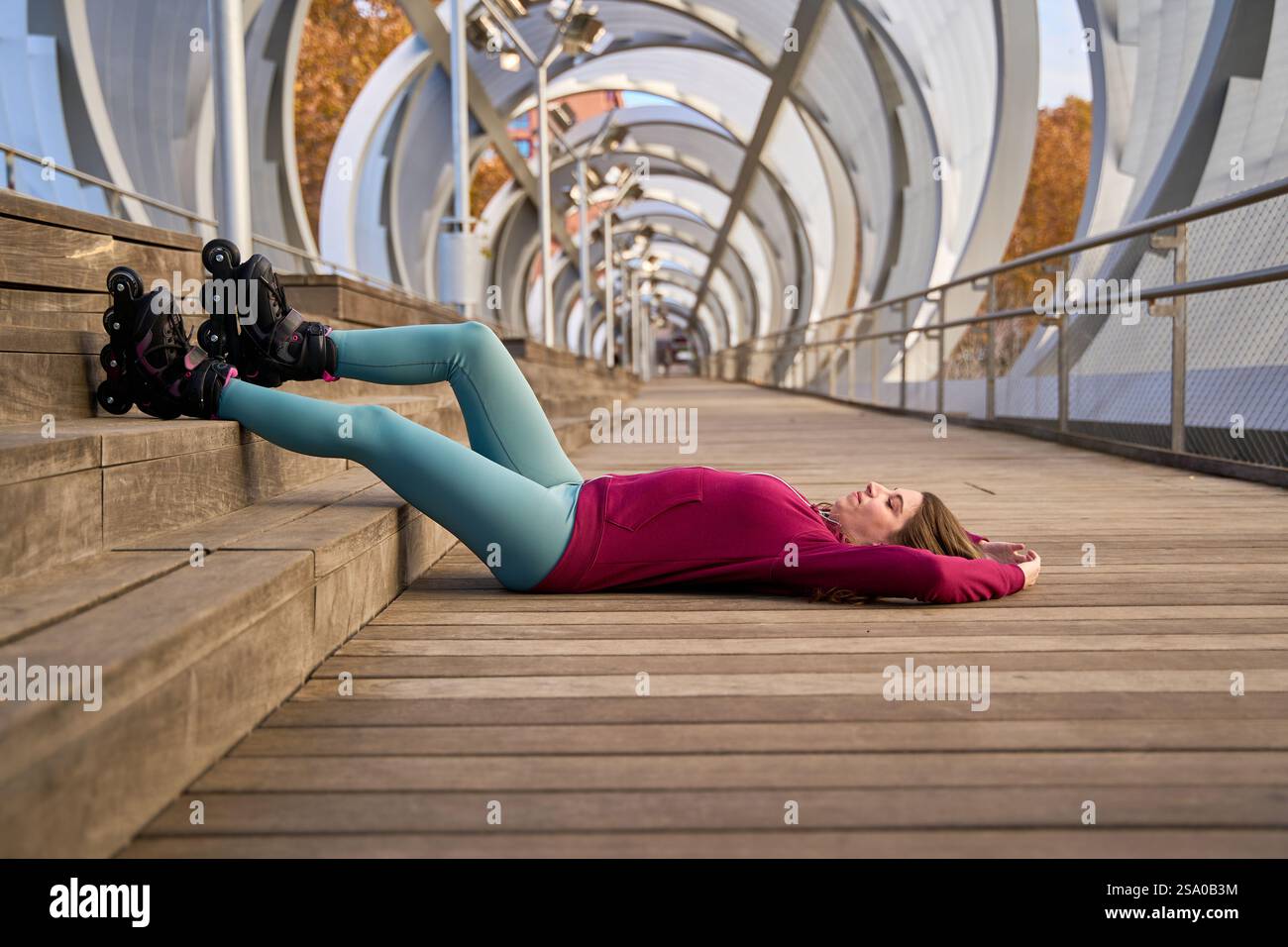 Young woman wearing inline skates is lying on the ground of a modern ...