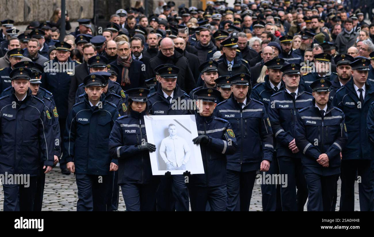 28 January 2025, Saxony, Dresden: Police officers carry a portrait ...