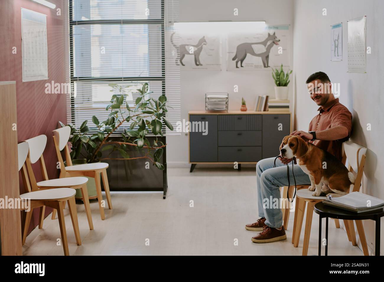 Man sitting in veterinarian's waiting room with dog on lap, surrounded ...