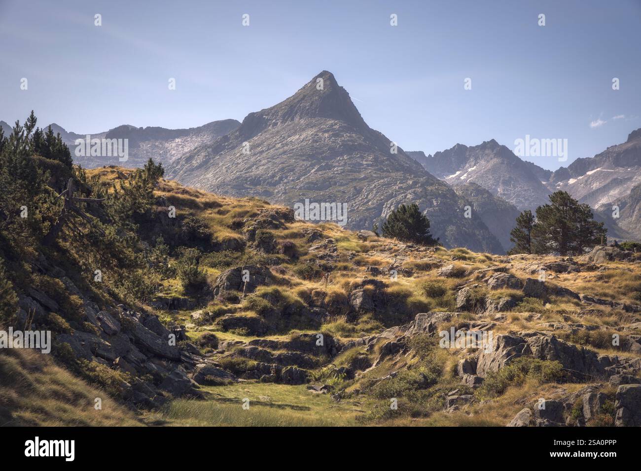 Lush valleys embrace towering peaks under a clear blue sky in the ...