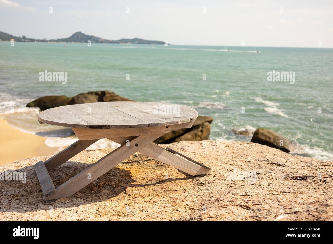 There is a wooden table on the stone surface overlooking the ocean. In ...