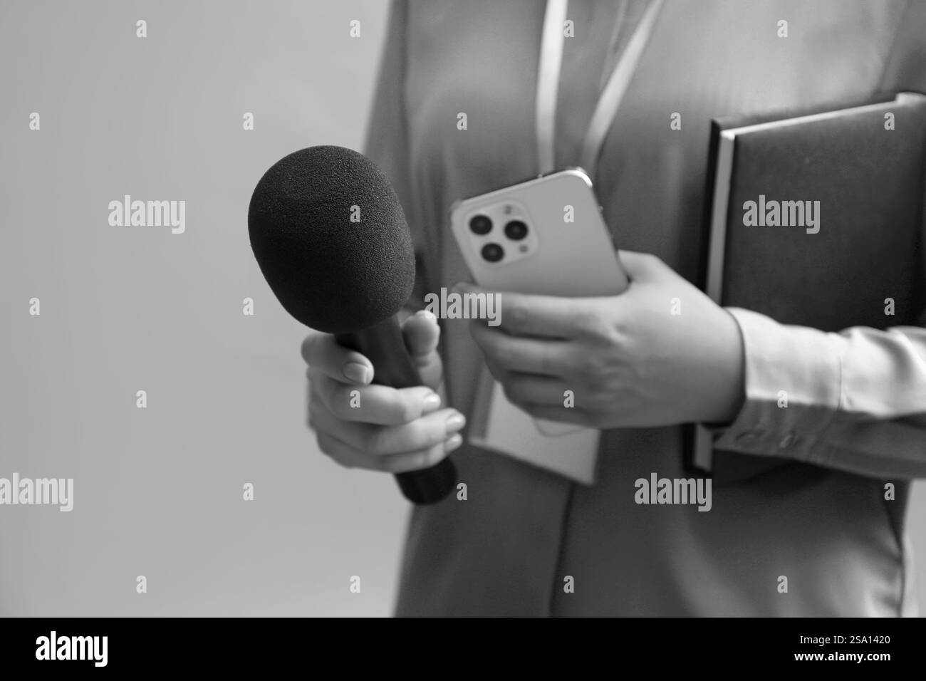 Journalist with microphone, mobile phone and notebook taking interview ...