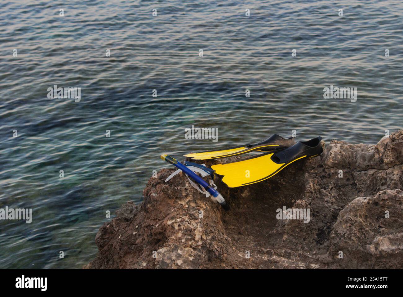 Yellow fins and snorkel mask on the sea rocks. Water sports in natural ...
