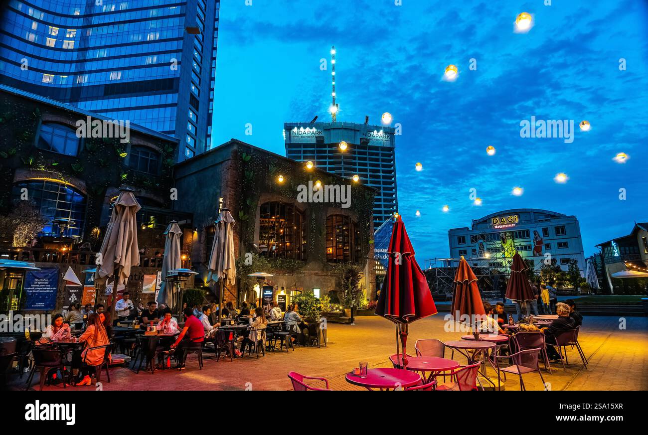 Bustling urban square during evening hours, showcasing modern architectural settings and public ...