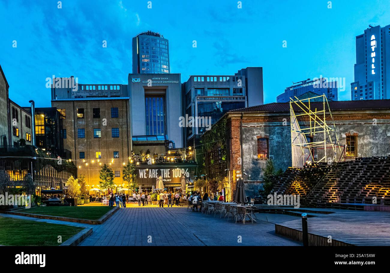 Bustling urban square during evening hours, showcasing modern architectural settings and public ...