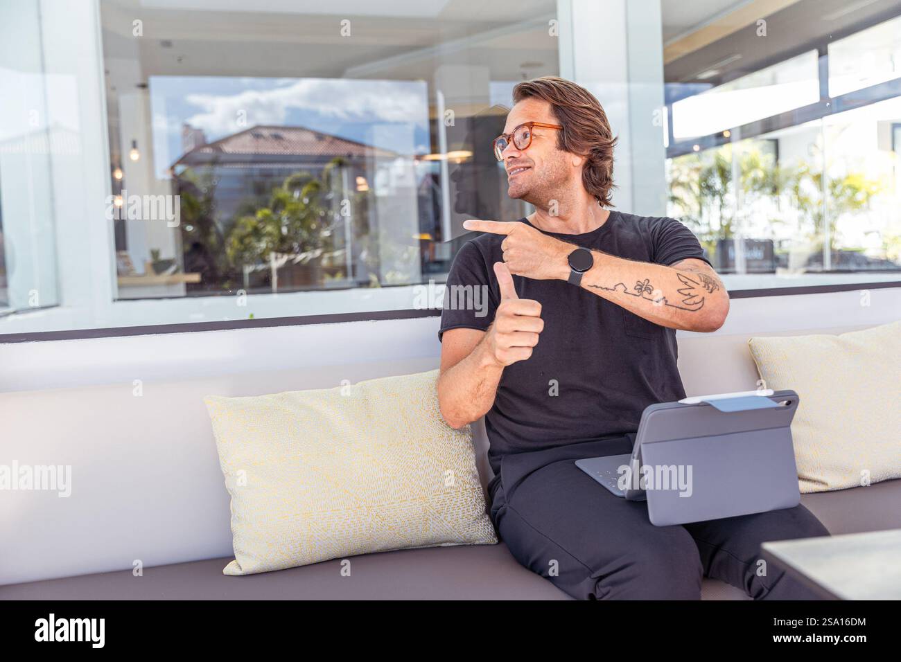 A businessman is giving a thumbs up gesture and points to the lest ...