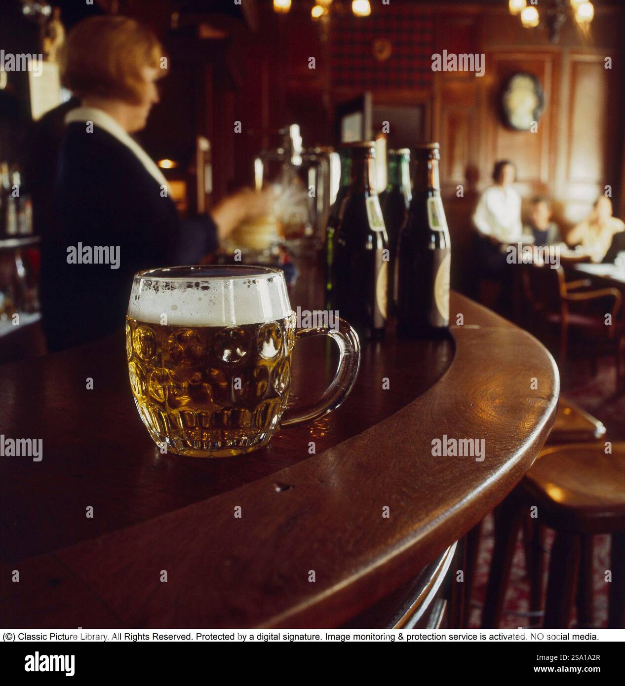 Pub in the 1960s. A pint of beer on the counter with beer bottles and a ...