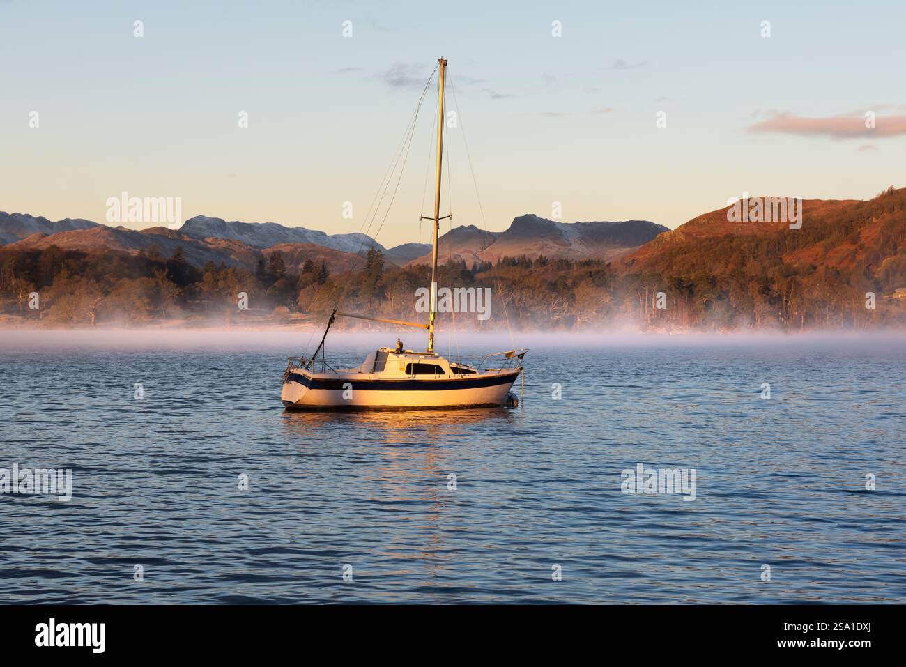 A lone small sailing boat moored on Lake Windermere on a beautiful blue ...