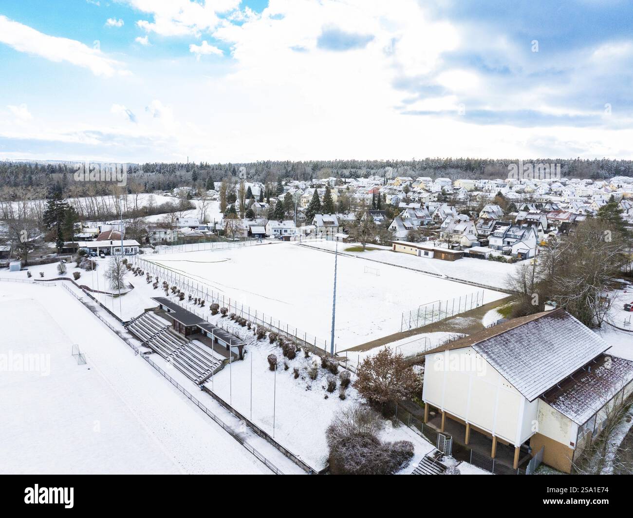 Snow-covered sports field with surrounding houses and buildings in a ...